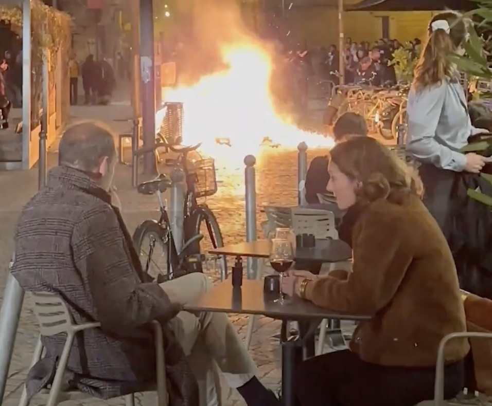 Bordeaux diners drink wine as protest fire rages in background